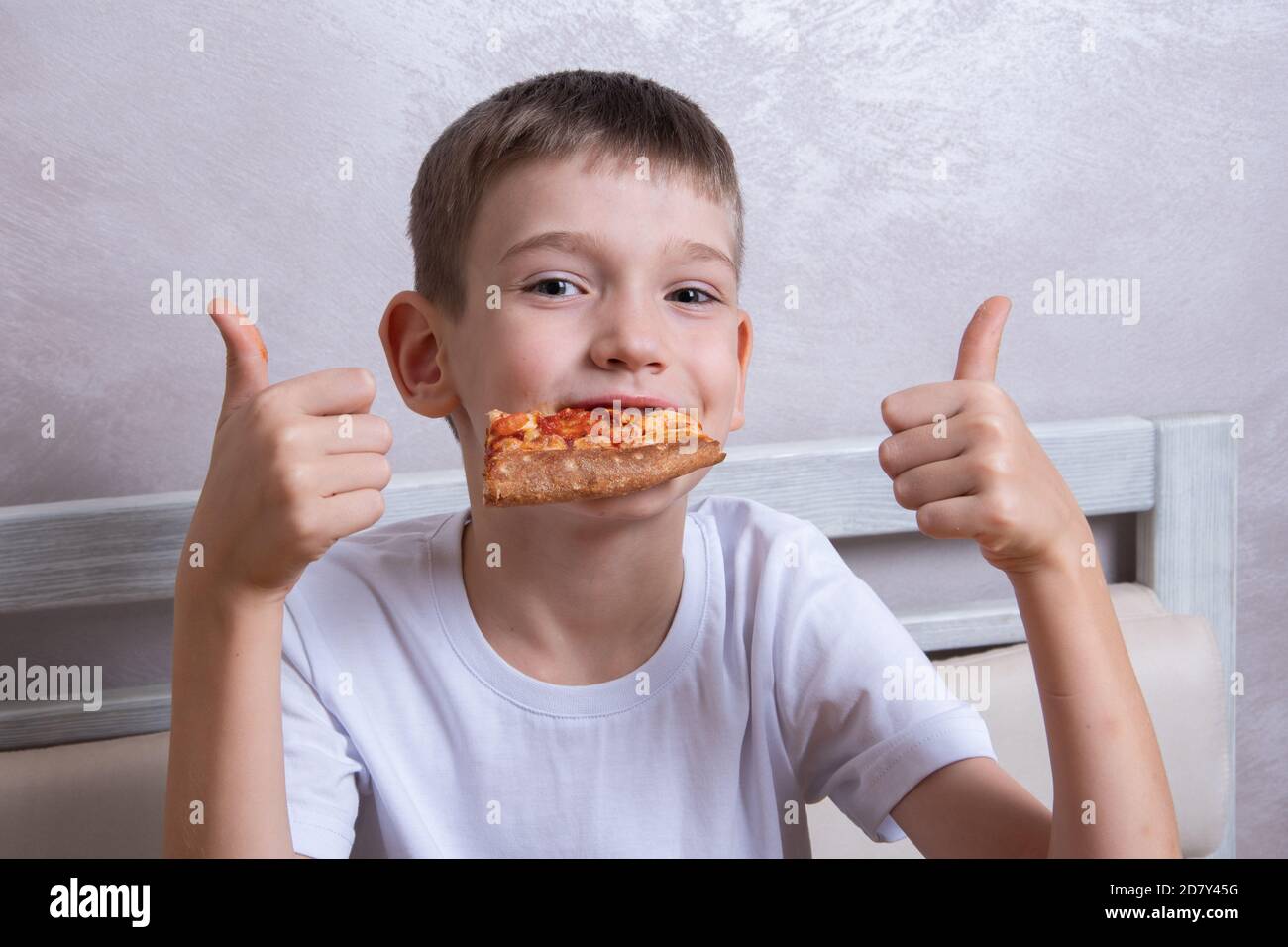 Cute boy eating a slice of pepperoni and cheese pizza and showing with ...