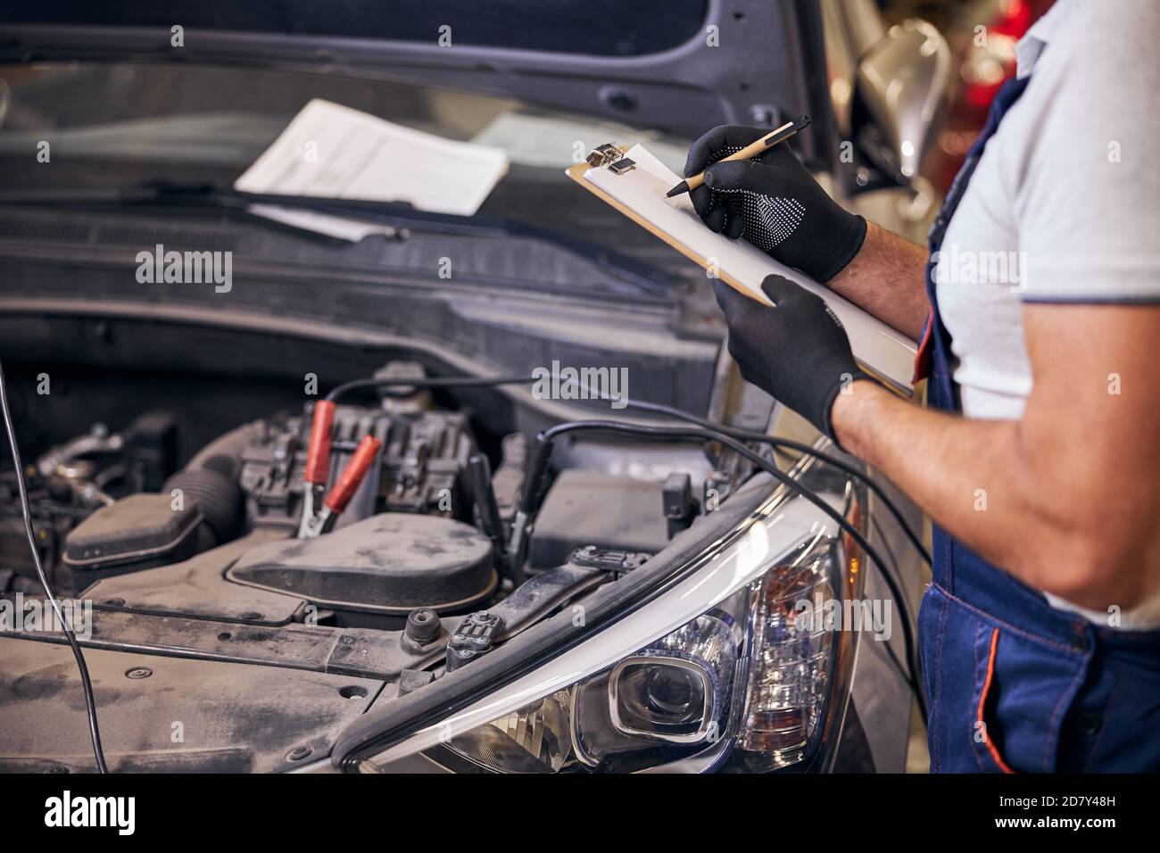 Auto mechanic writing on clipboard in automobile repair shop Stock ...