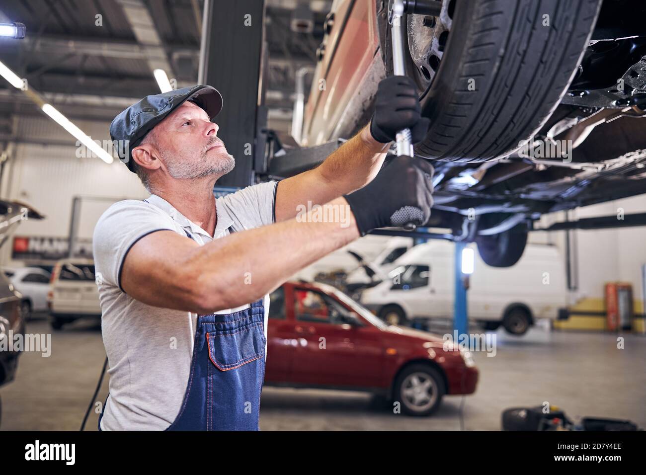 Bearded mechanic repairing car wheel at auto service station Stock ...