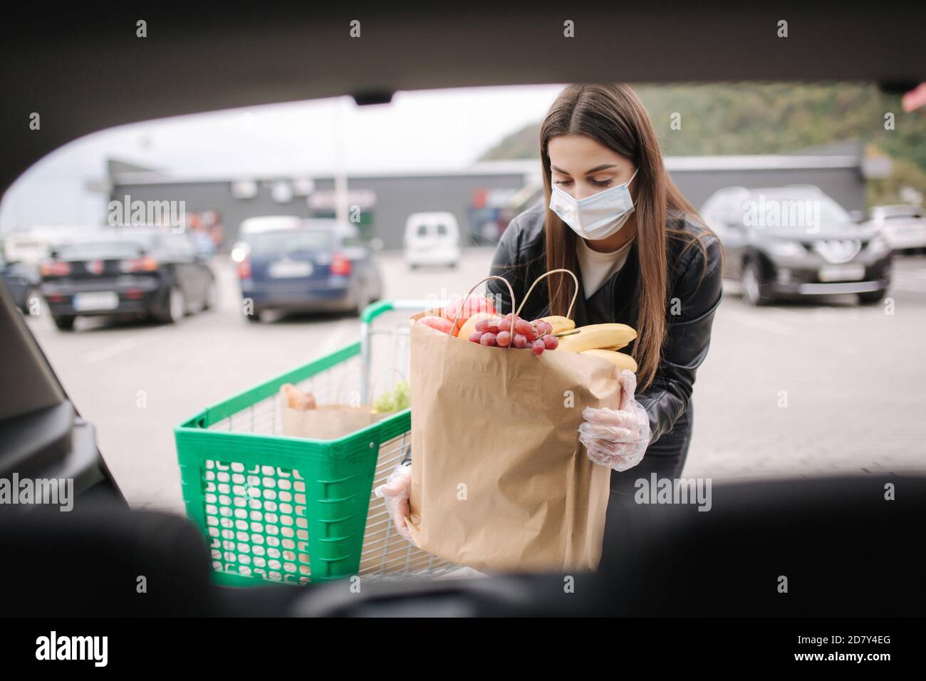 Over trunk view of young woman in medical mask in masks loading bags in ...