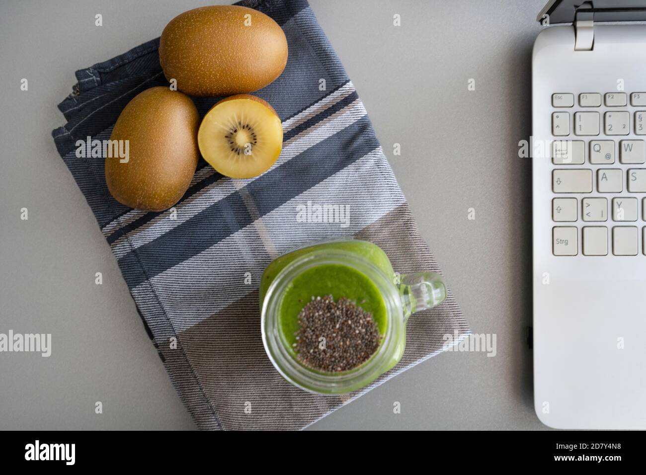 Healthy workplace with green smoothie and laptop on gray background ...