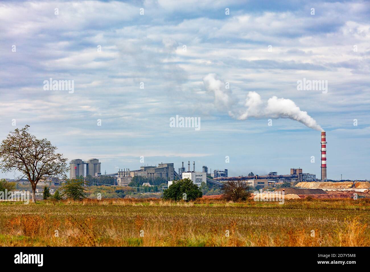Cement plant on the horizon with a smoking chimney and a quarry amid ...