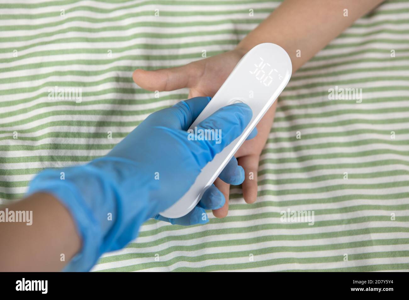 Doctor measures temperature of child on arm with electronic thermometer ...