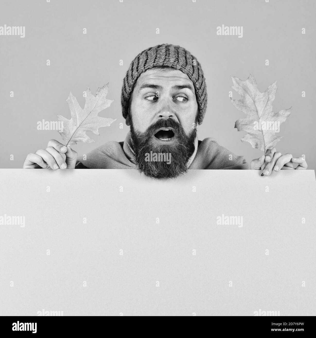 Hipster with beard and scared face looks aside. Autumn and fallen ...