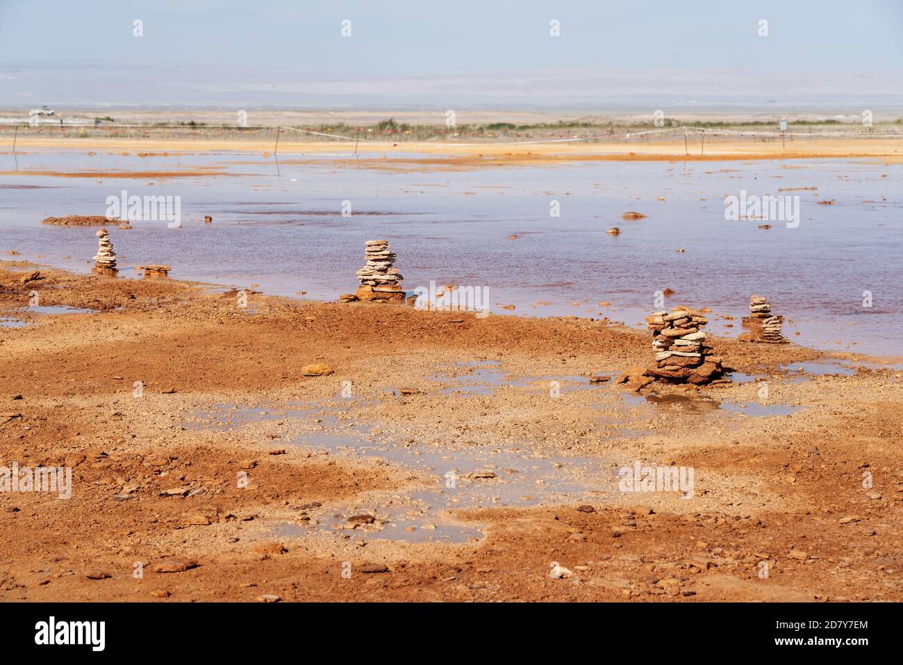 Muddy ground with spring water, with stacks of stones on one side ...