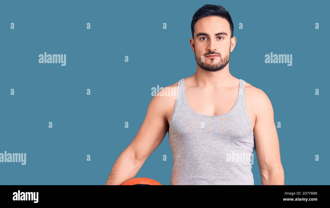 Young handsome man holding basketball ball thinking attitude and sober ...