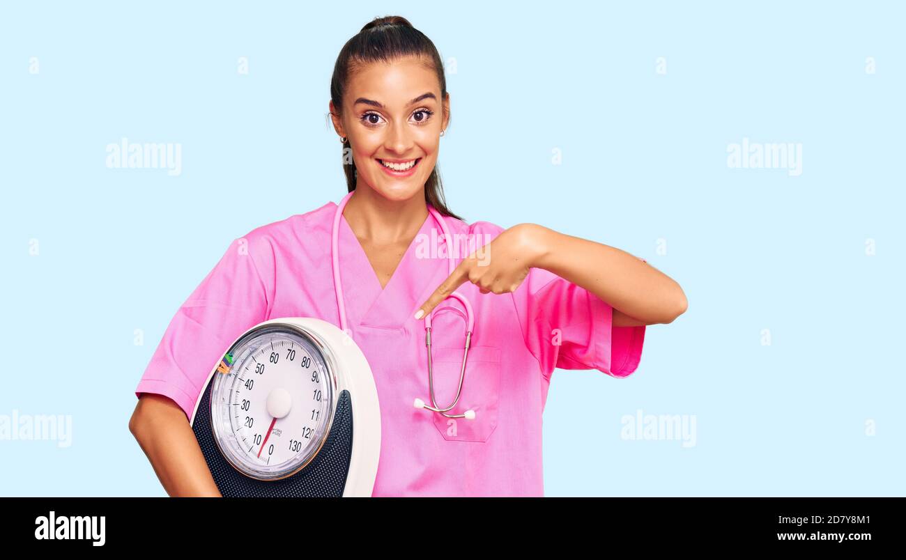 Young hispanic woman as nutritionist doctor holding weighing machine ...