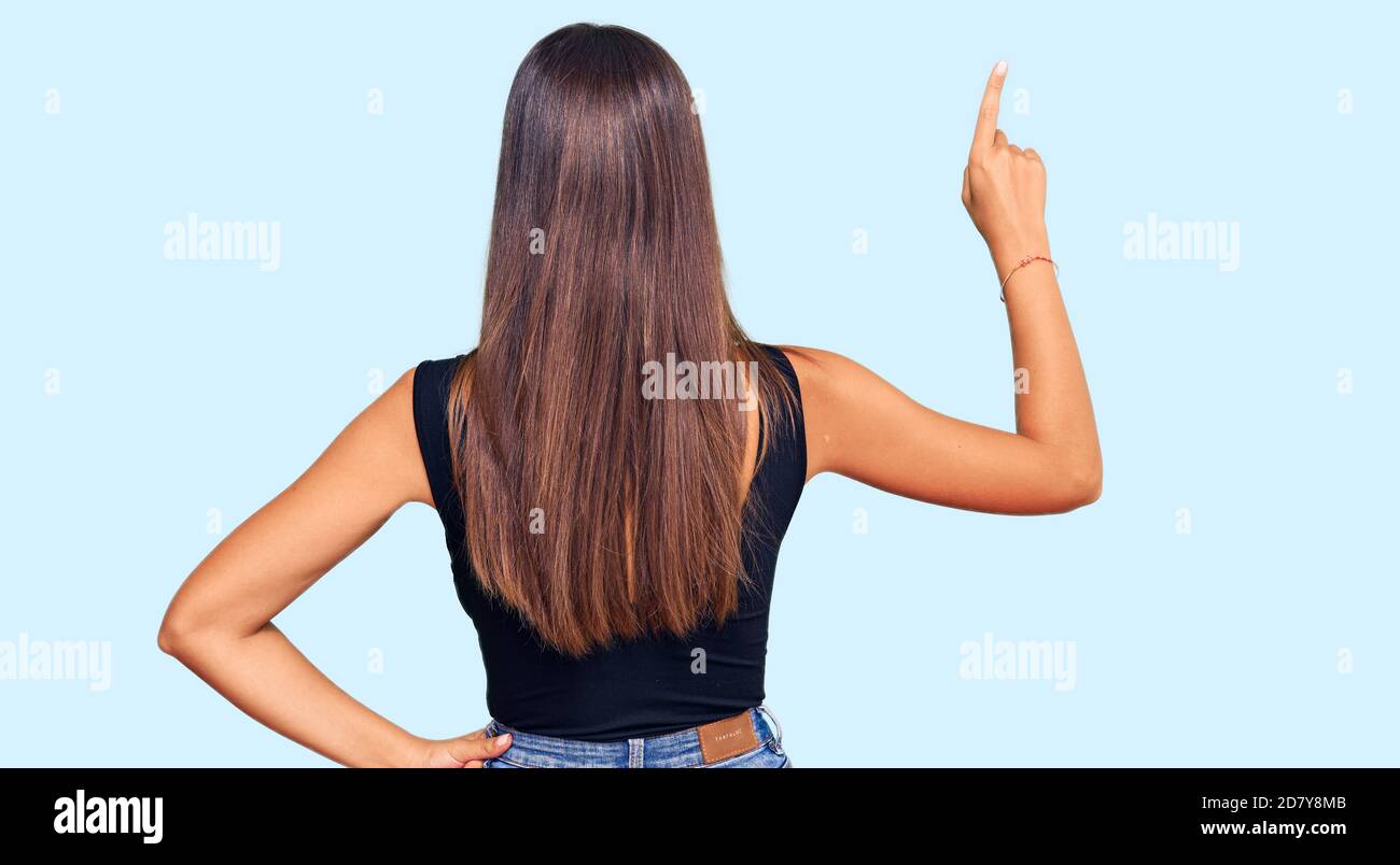 Young hispanic woman wearing casual clothes posing backwards pointing ...