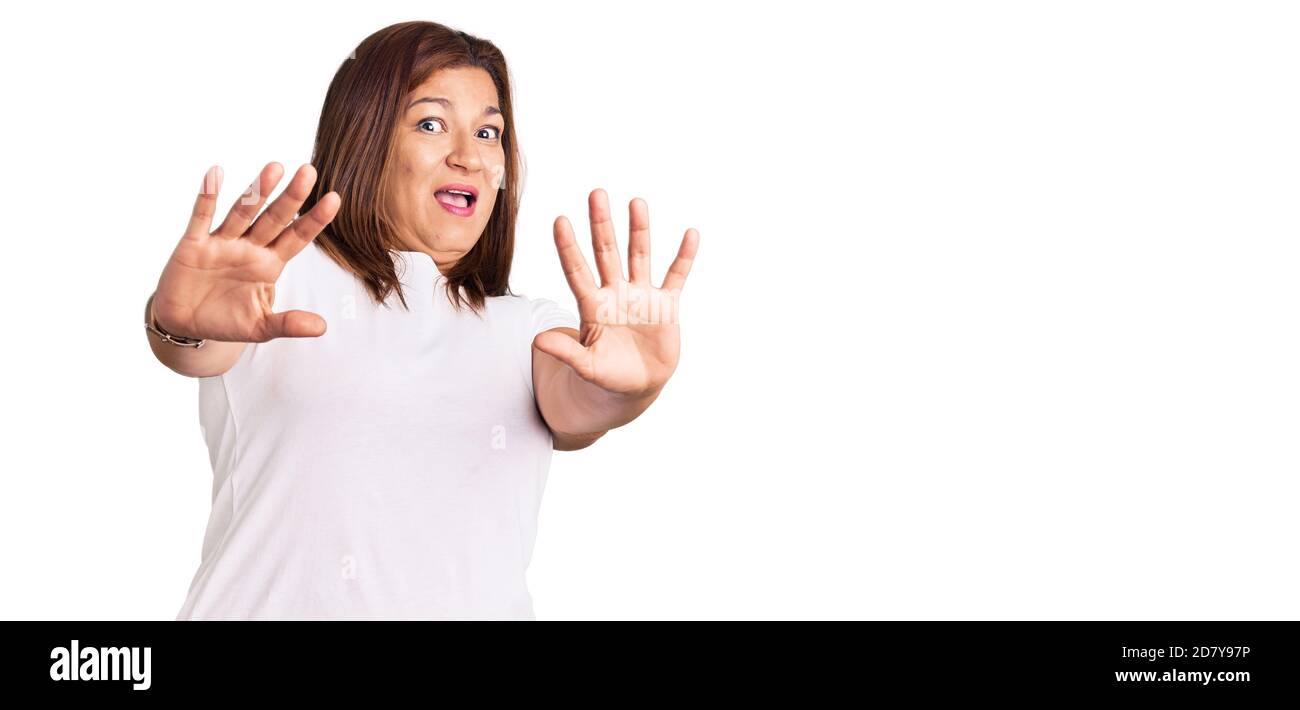 Middle age latin woman wearing casual white tshirt afraid and terrified ...