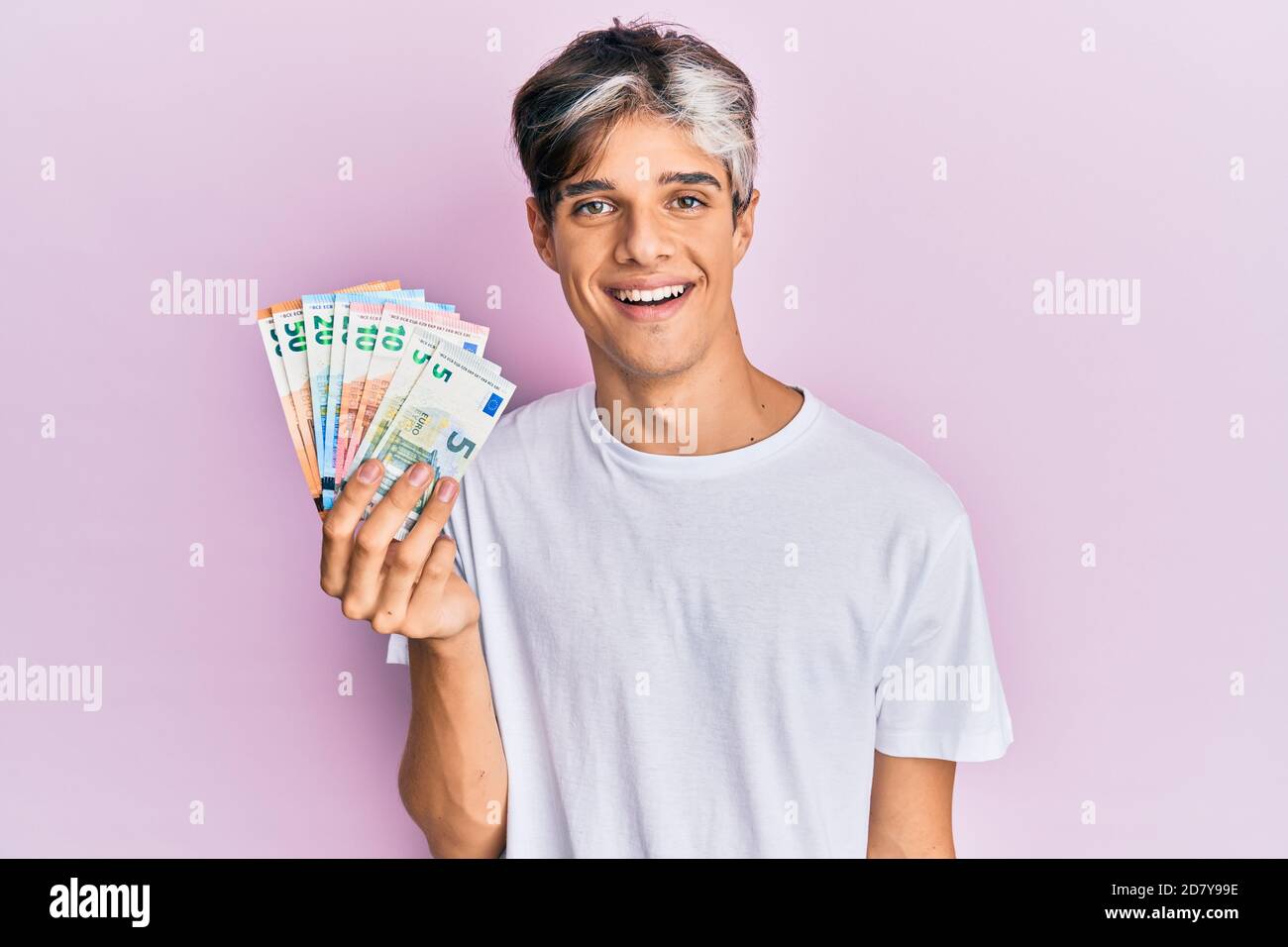 Young hispanic man holding euro banknotes looking positive and happy ...
