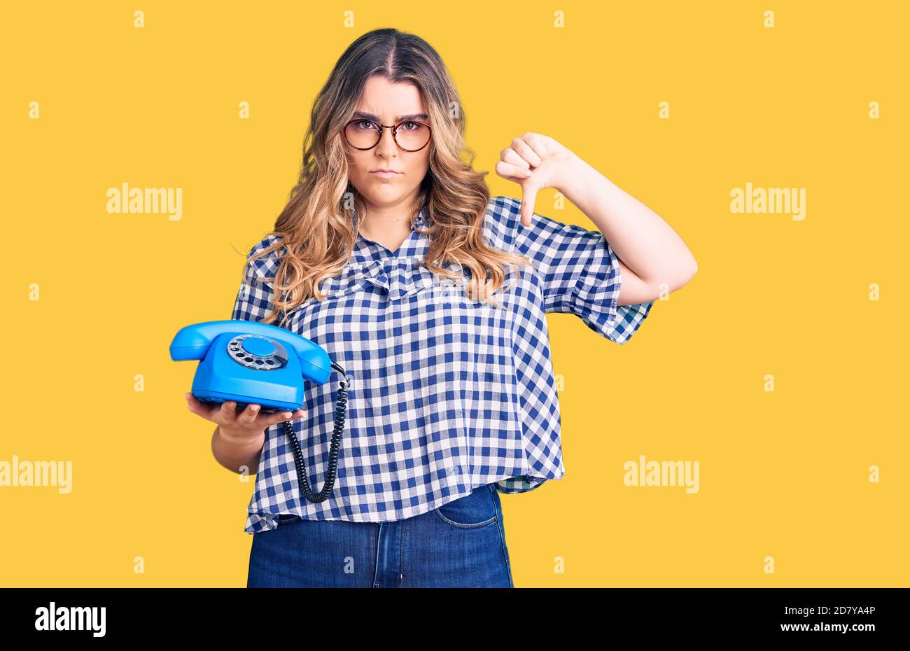 Young caucasian woman holding vintage telephone with angry face ...