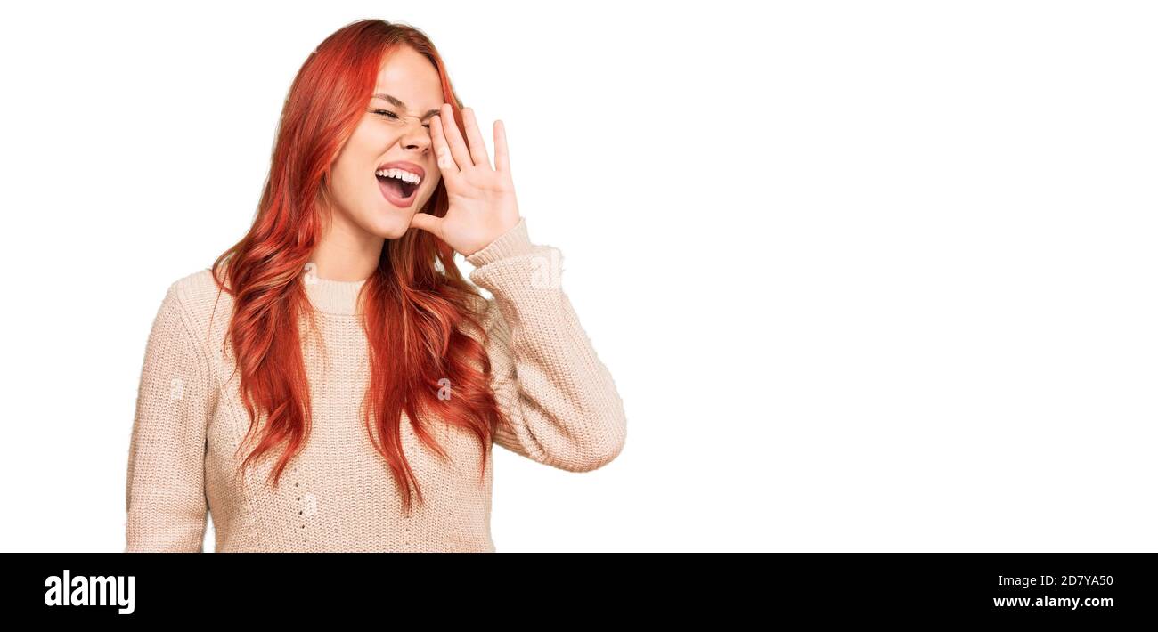 Young redhead woman wearing casual winter sweater shouting and ...