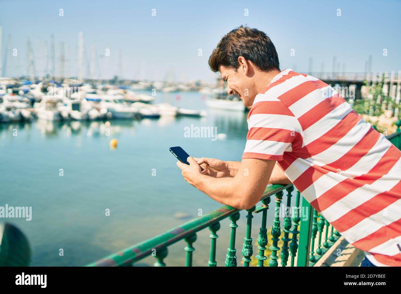 Young caucasian man smiling happy using smartphone leaning on the ...
