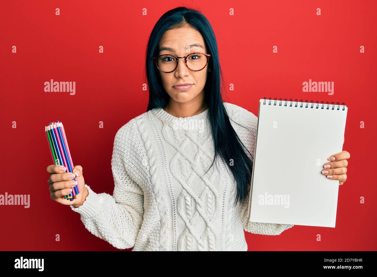 Beautiful hispanic woman holding canvas book and colored pencils ...