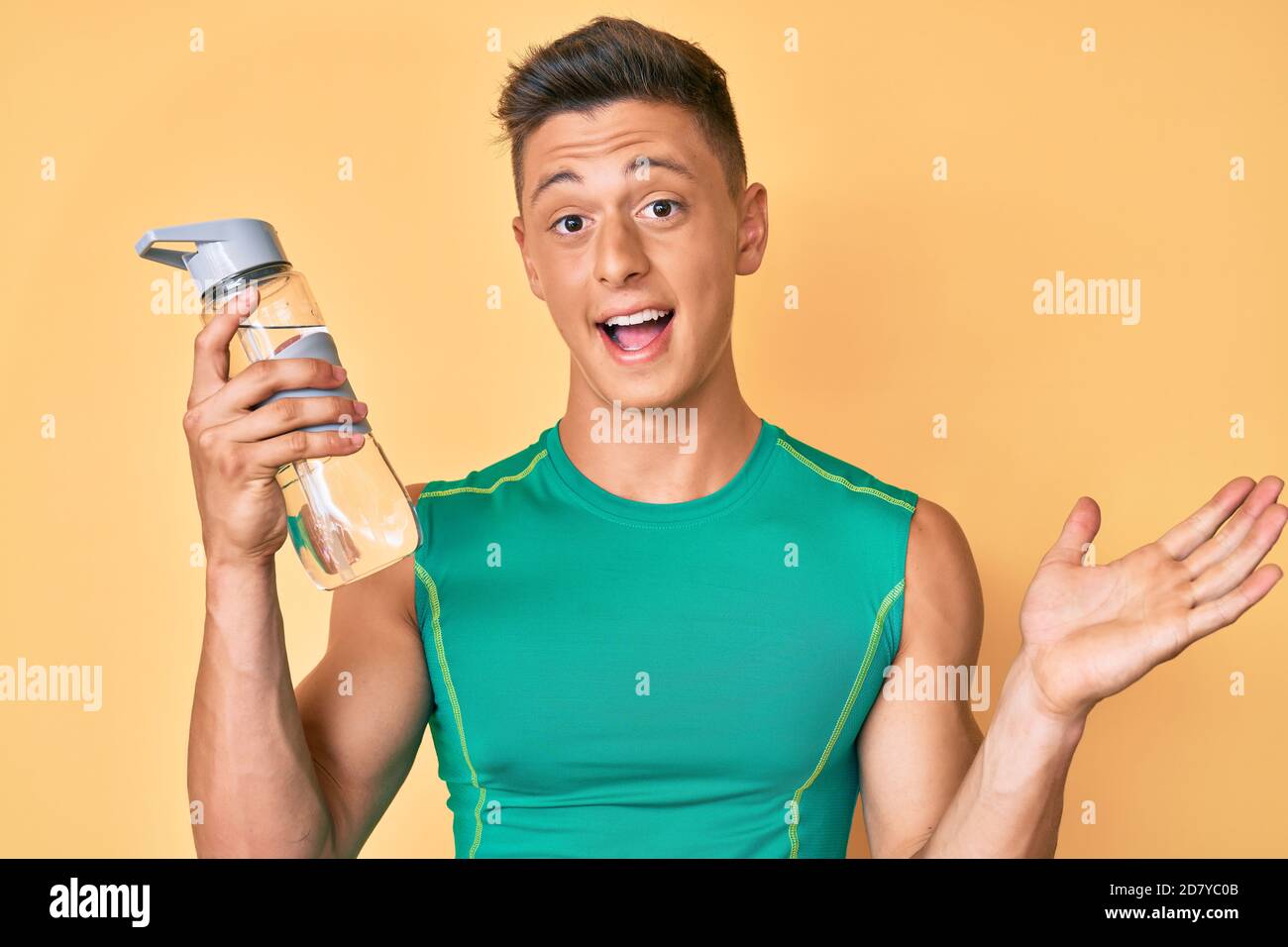 Young hispanic boy wearing sportswear holding water bottle celebrating ...