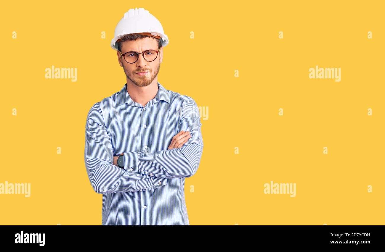 Handsome young man with bear wearing architect hardhat skeptic and ...