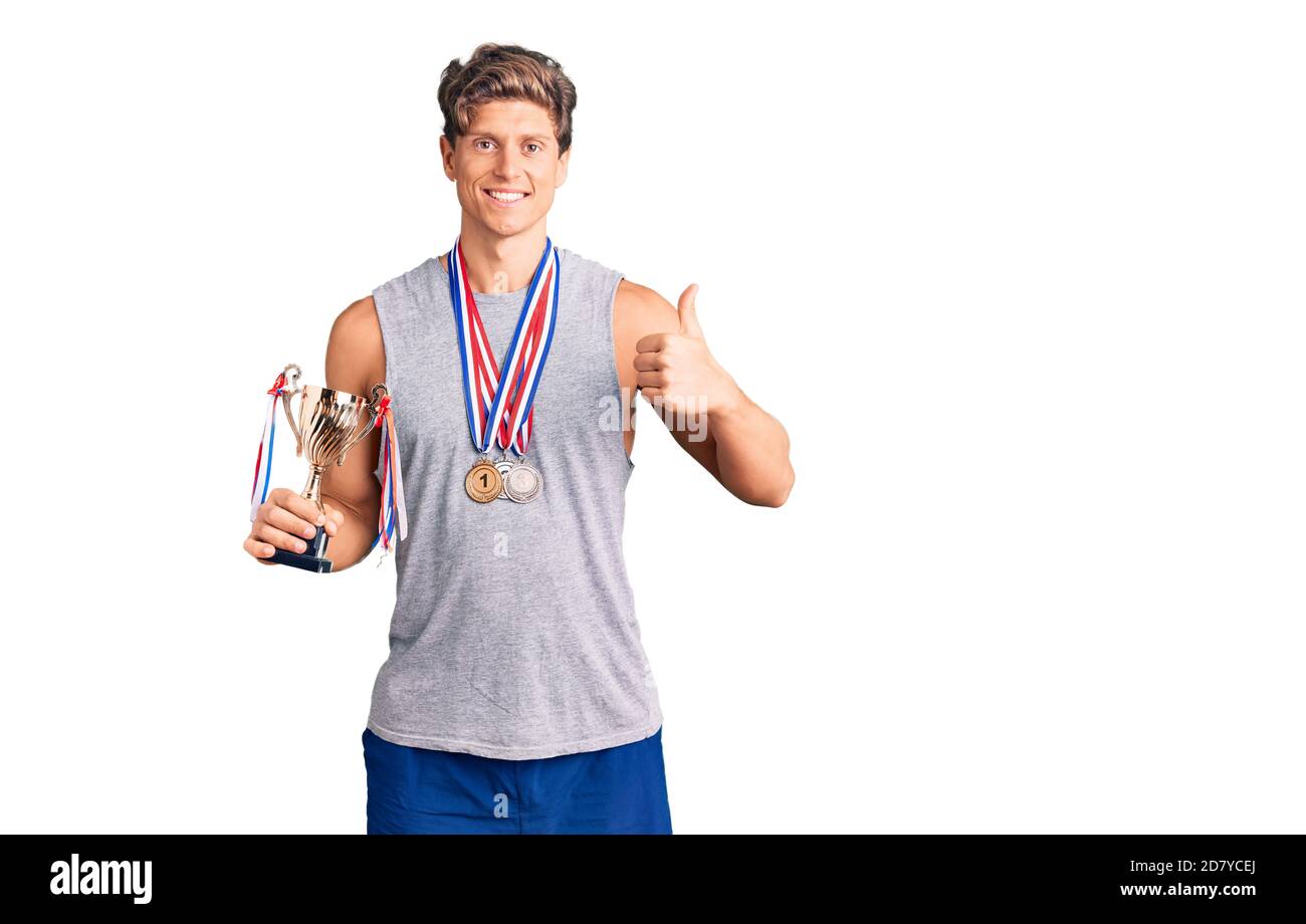 Young handsome man holding champion trophy wearing medals smiling happy ...