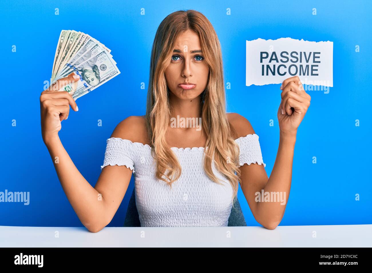 Beautiful blonde young woman holding dollars and passive income text ...