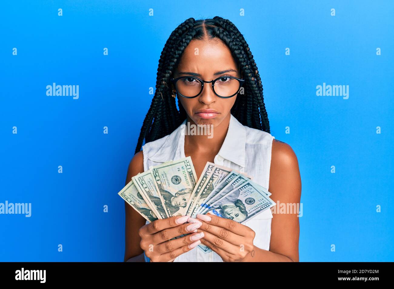 Beautiful hispanic woman holding dollars depressed and worry for ...