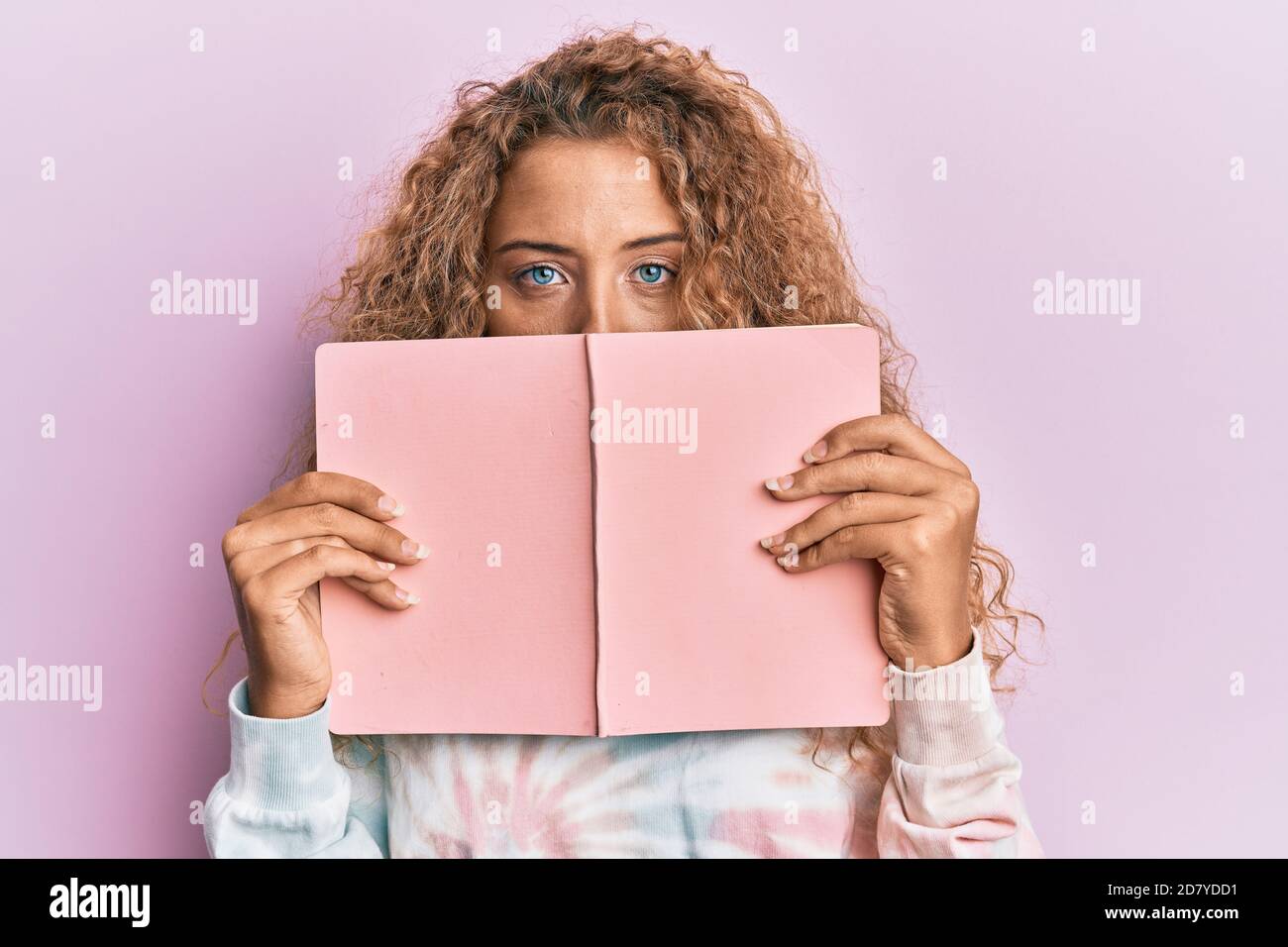 Beautiful caucasian teenager girl reading a book covering face ...