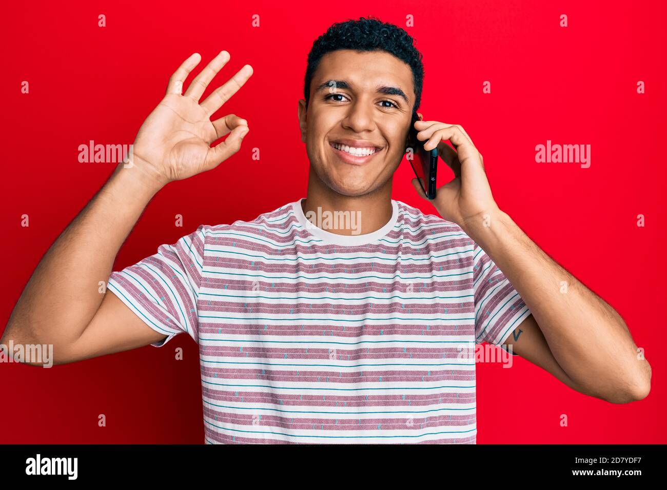 Young arab man having conversation talking on the smartphone doing ok ...