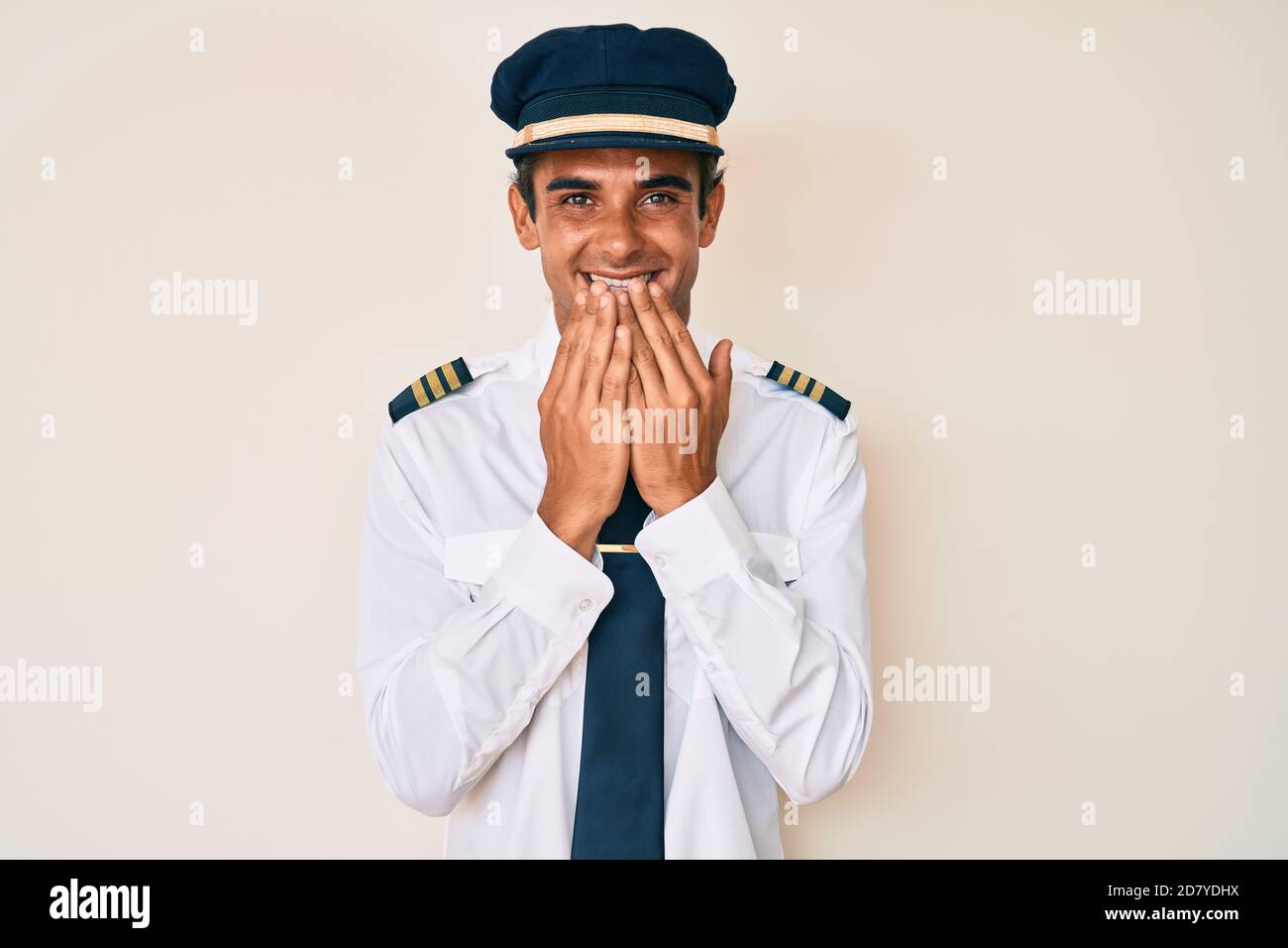 Young hispanic man wearing airplane pilot uniform laughing and ...