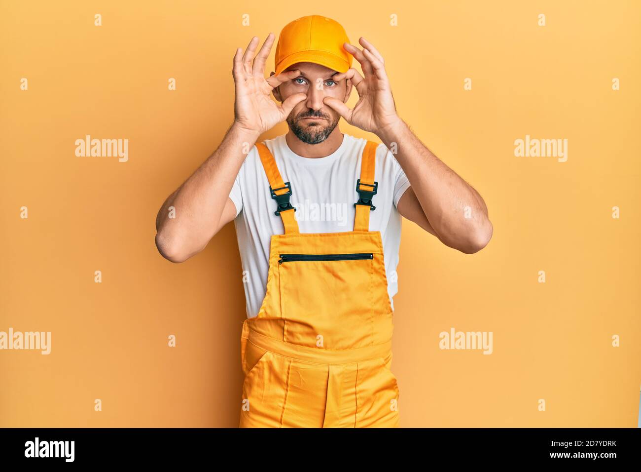 Young handsome man wearing handyman uniform over yellow background ...