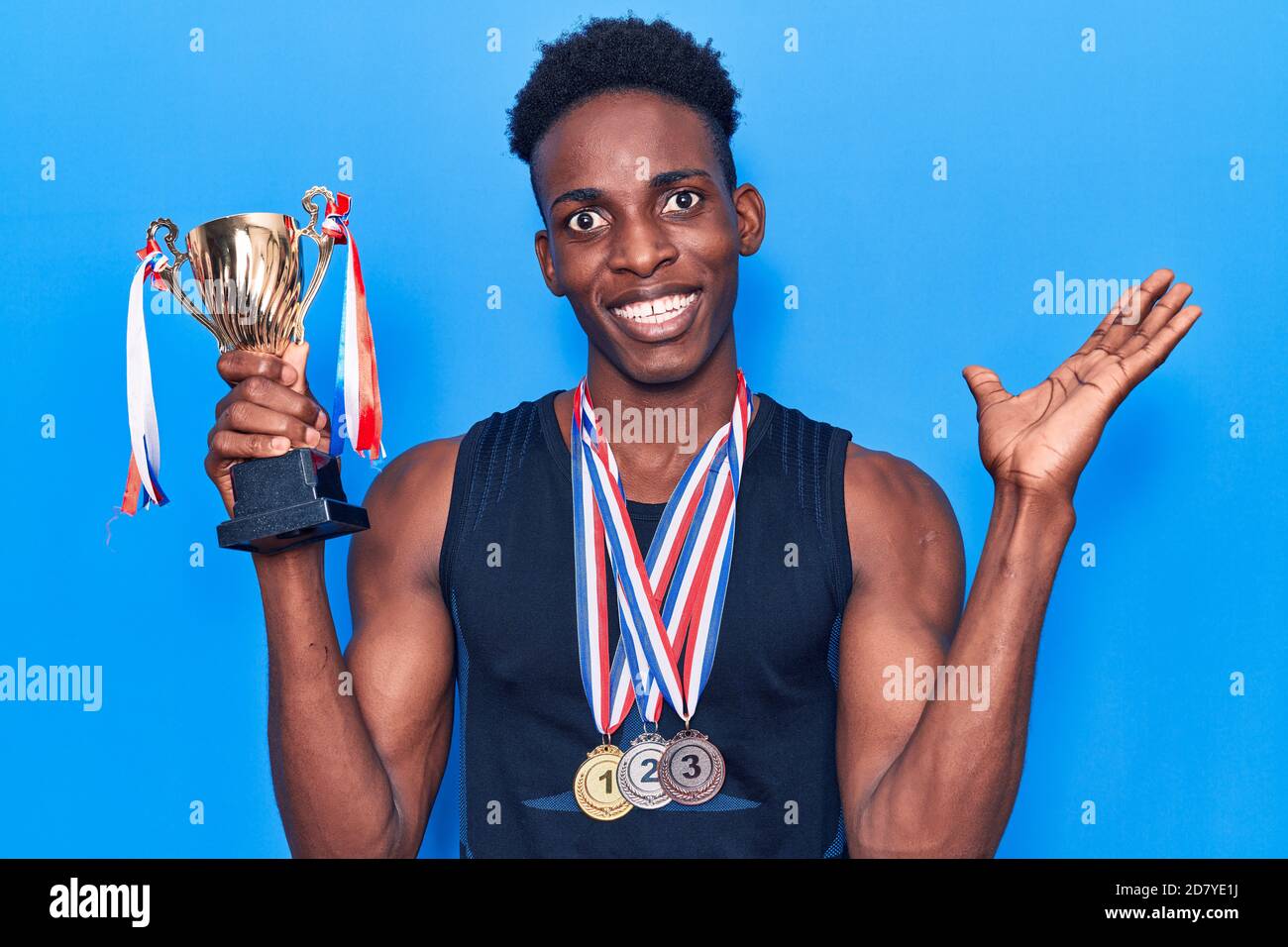 Young african american man holding champion trophy wearing medals ...