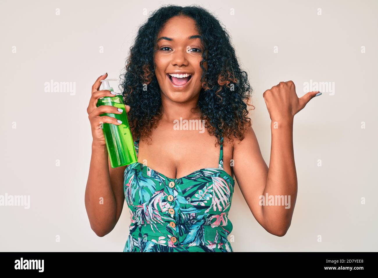 Young african american woman holding aloe vera pointing thumb up to the ...