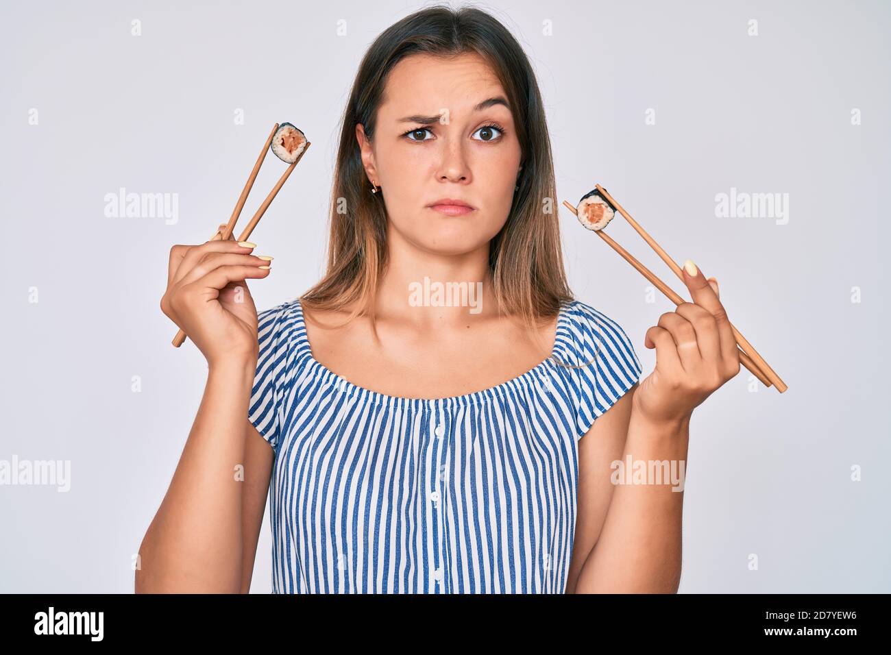 Beautiful caucasian woman eating sushi using chopsticks skeptic and ...
