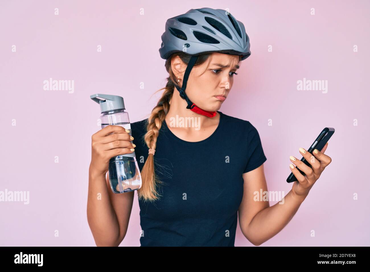 Beautiful caucasian woman wearing bike helmet looking at smartphone ...