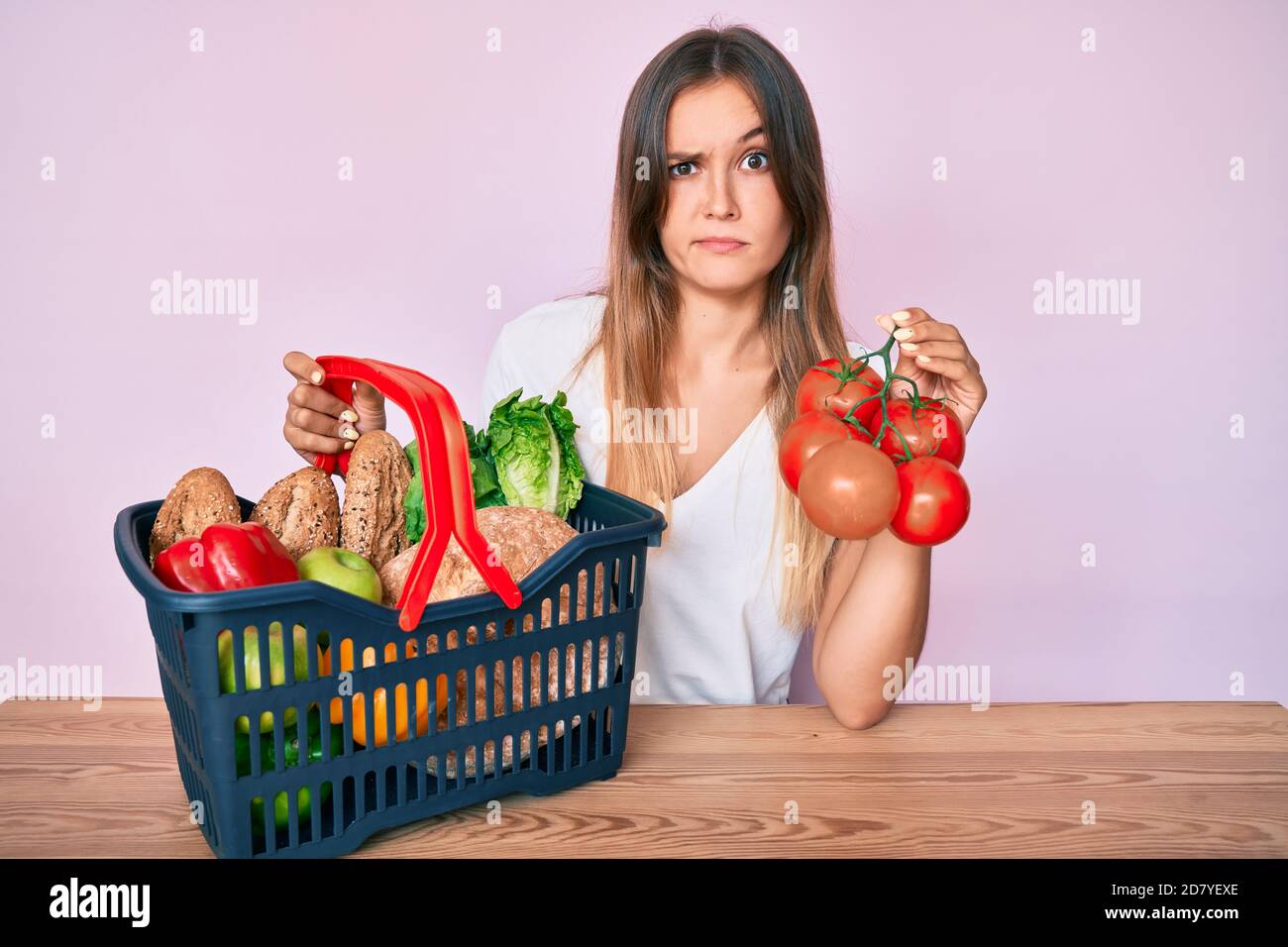 Beautiful caucasian woman holding supermarket shopping basket and ...