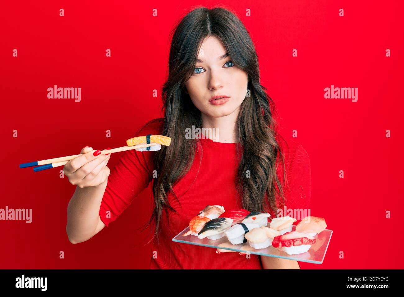 Young beautiful caucasian girl eating sushi using chopsticks clueless ...