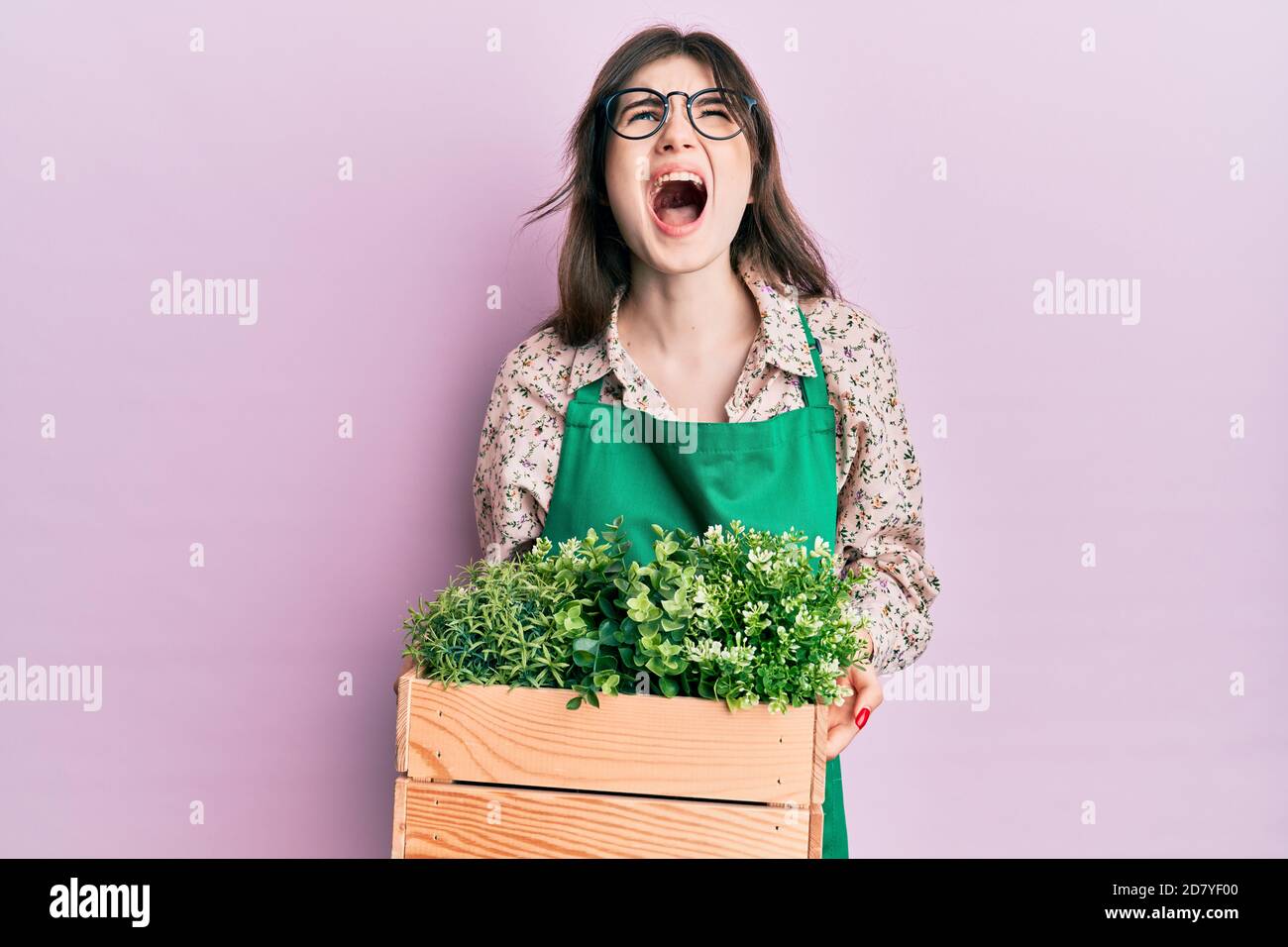 Young beautiful caucasian girl wearing gardener apron holding wooden ...