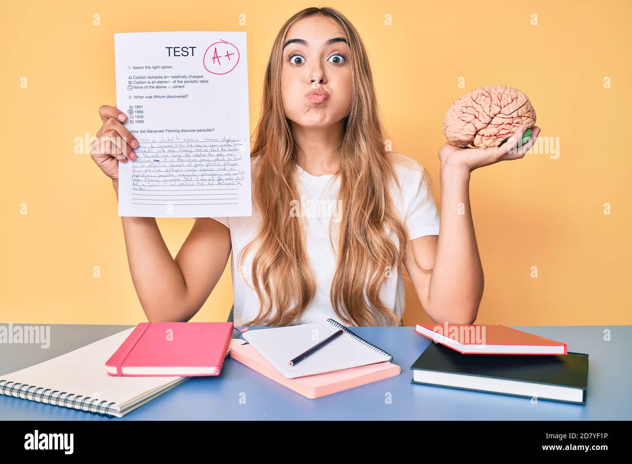 Young beautiful blonde woman holding brain and passed test puffing ...