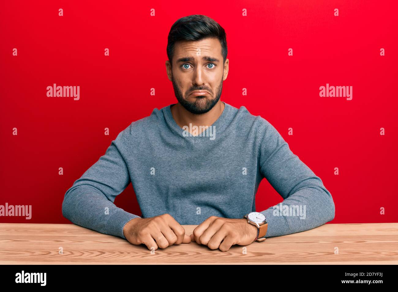 Handsome hispanic man wearing casual style sitting on the table ...