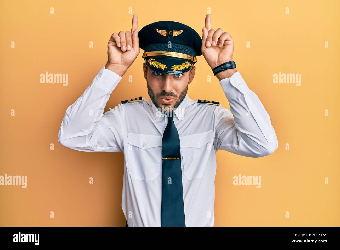 Handsome hispanic man wearing airplane pilot uniform doing funny ...