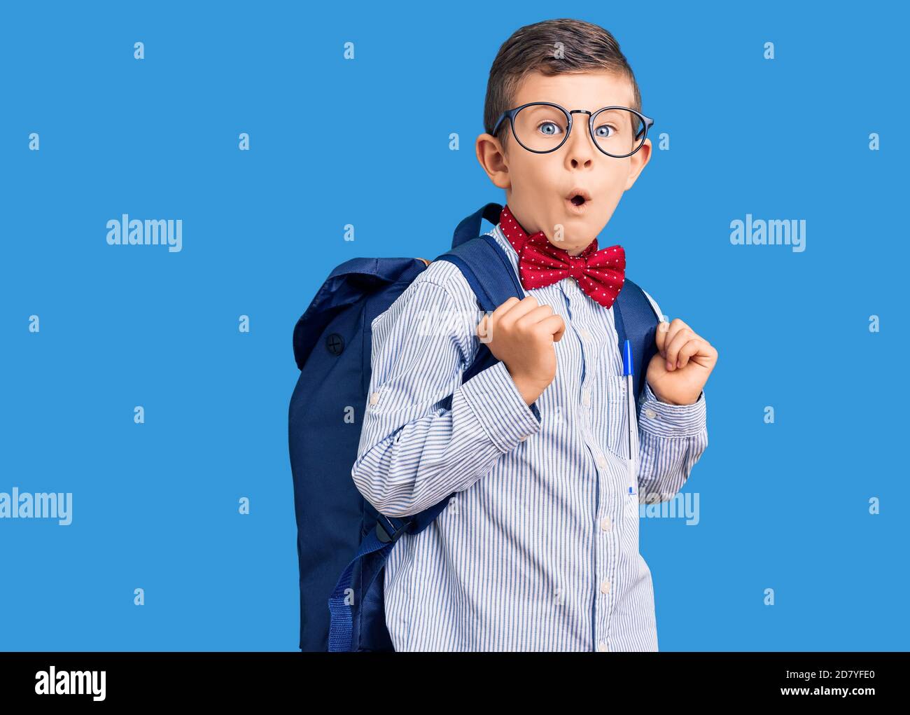 Cute blond kid wearing nerd bow tie and backpack scared and amazed with ...