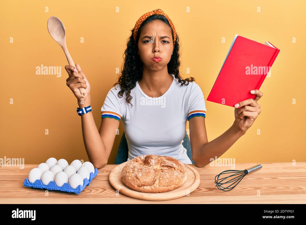 Young african american girl making homemade bread holding spoon and ...