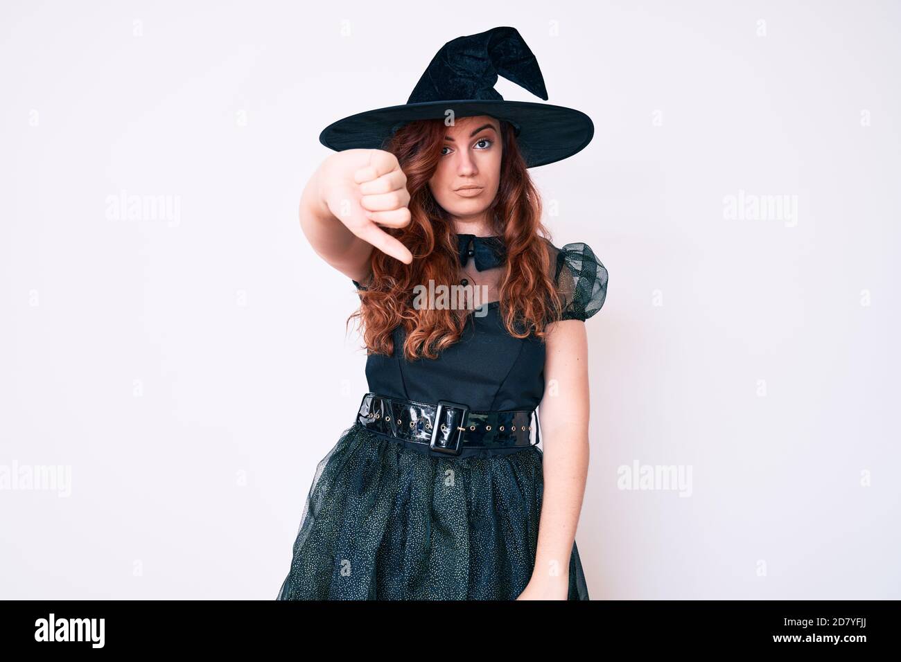 Young beautiful woman wearing witch halloween costume looking unhappy ...