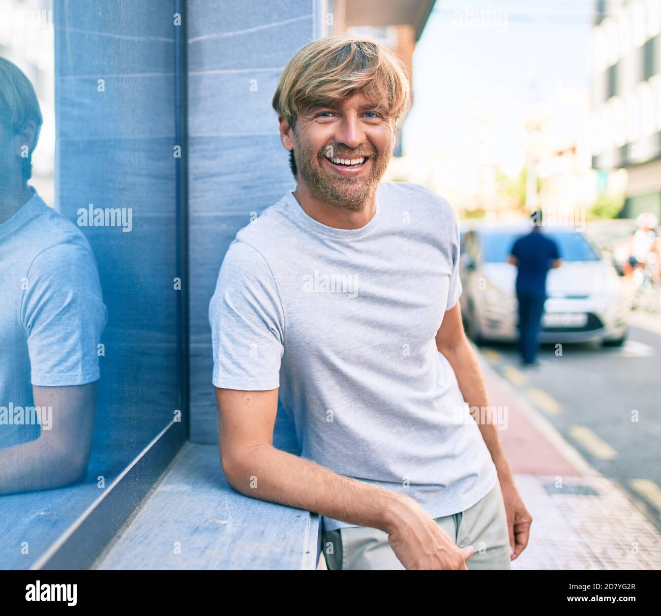 Young irish man smiling happy leaning on the wall at street of city ...