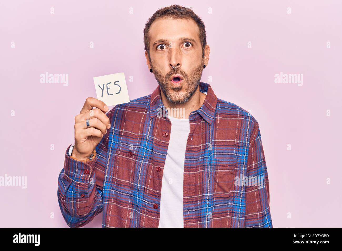 Young handsome man holding yes reminder scared and amazed with open ...