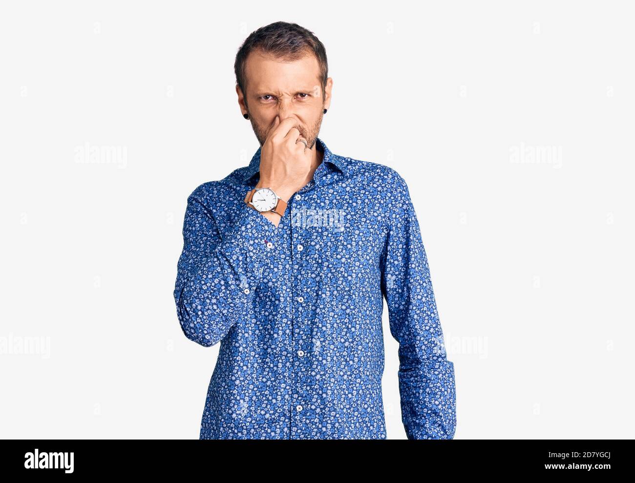 Young handsome man wearing casual clothes smelling something stinky and ...