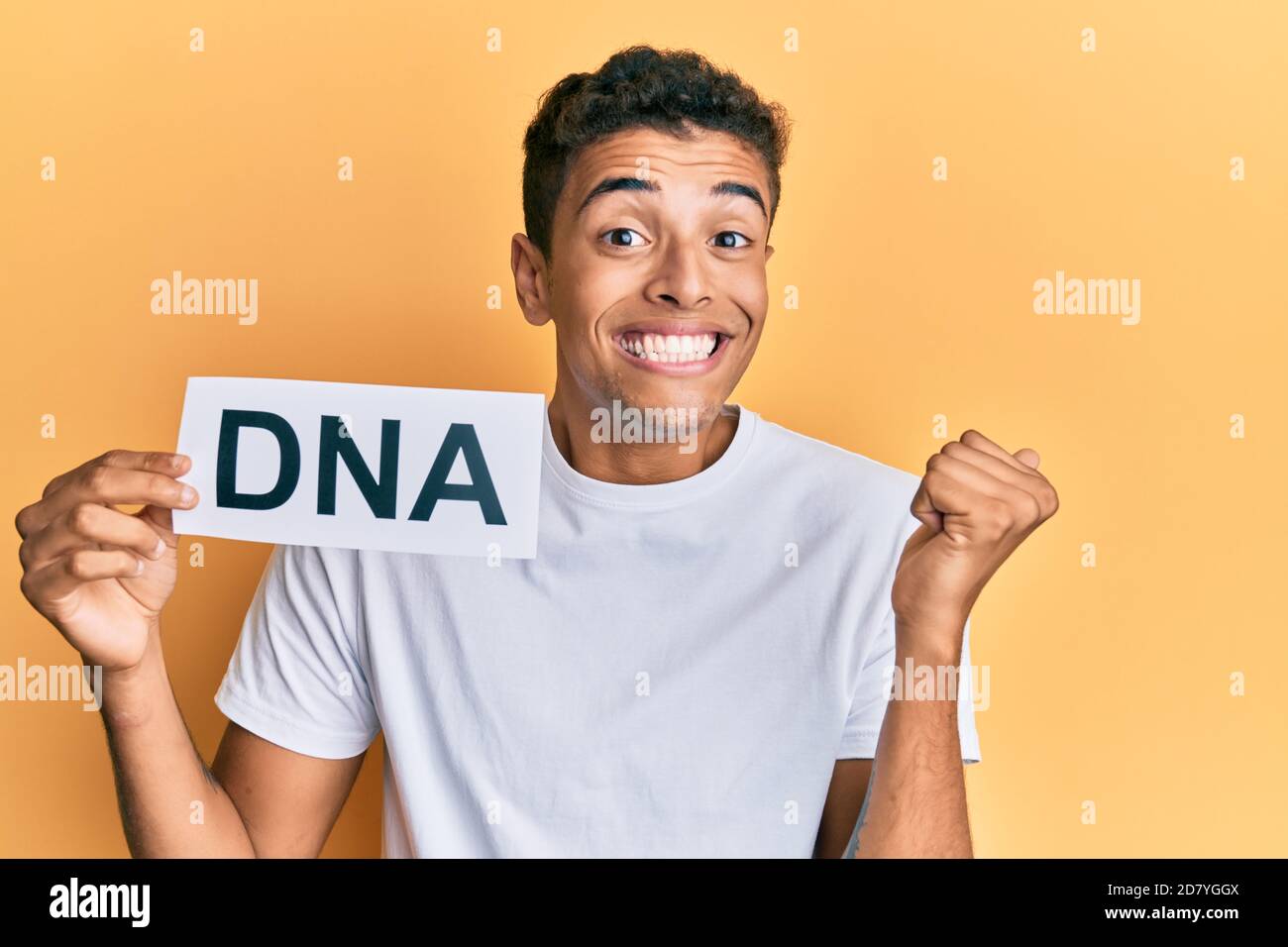 Young handsome african american man holding dna word screaming proud ...