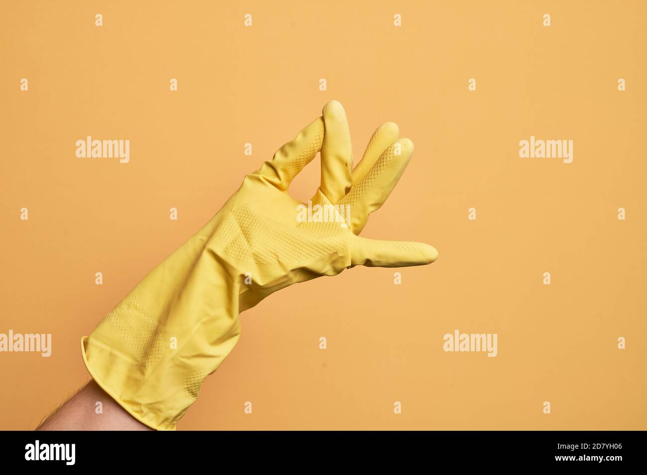 Hand of caucasian young man with cleaning glove over isolated yellow ...