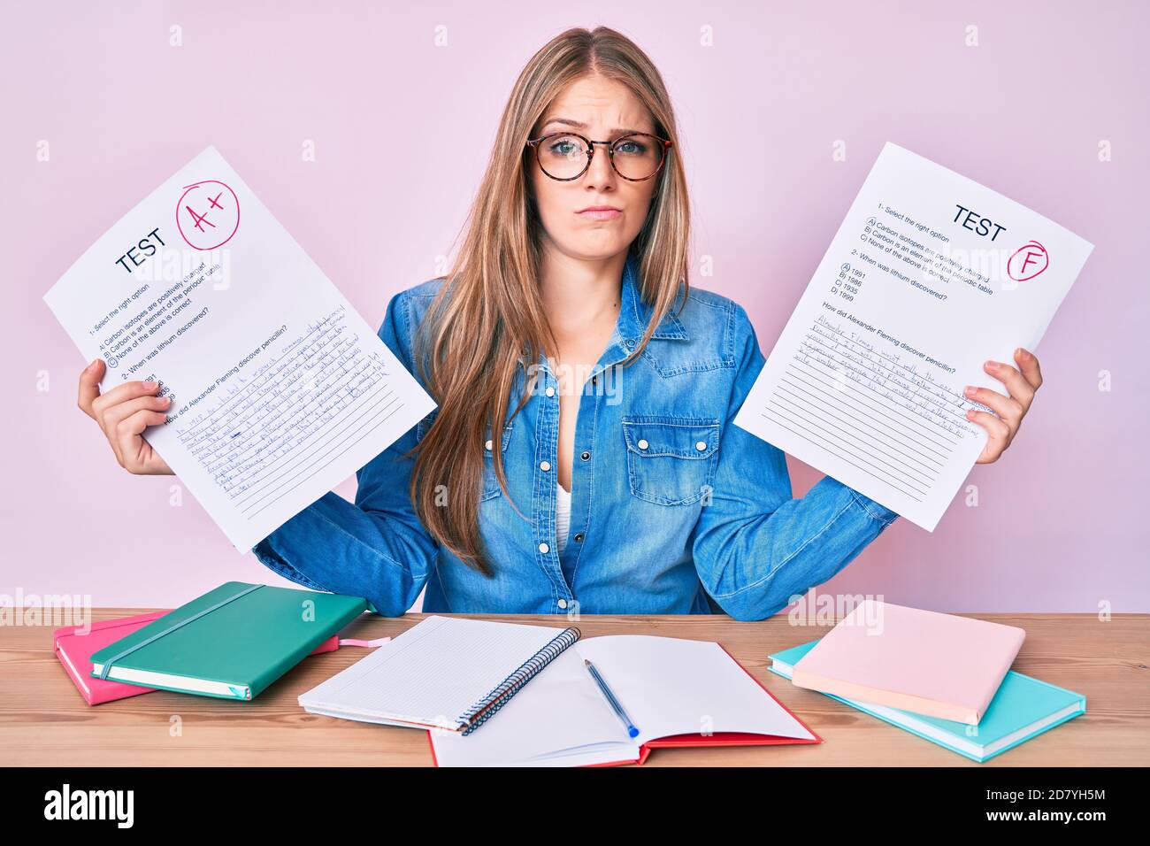 Young blonde girl showing failed and passed exams sitting on the table ...