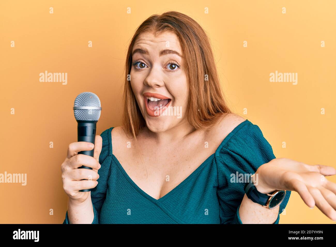 Young beautiful redhead woman singing song using microphone celebrating ...