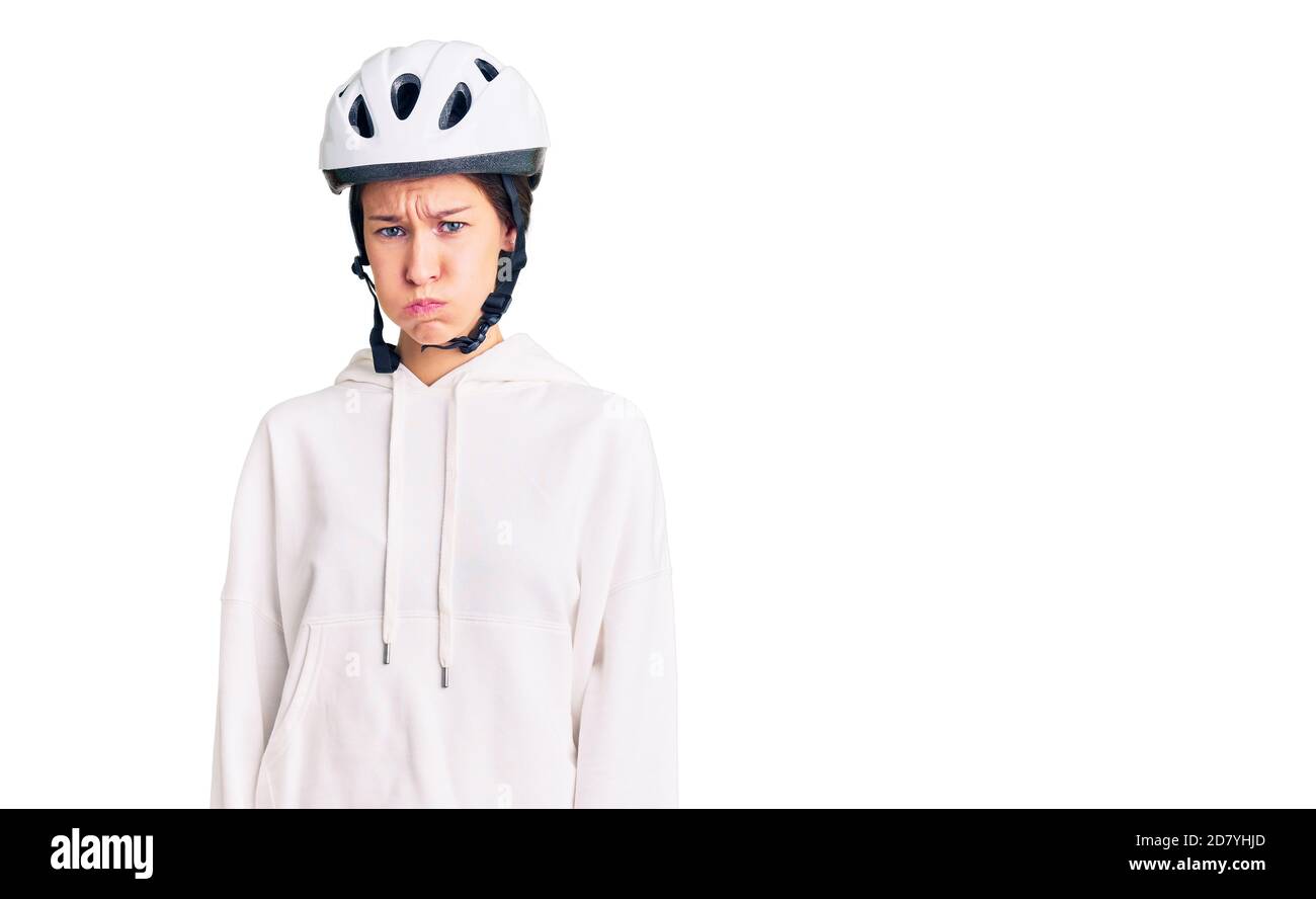 Beautiful brunette young woman wearing bike helmet and sporty clothes ...