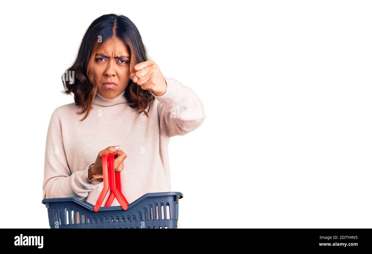 Young beautiful mixed race woman holding supermarket shopping basket ...