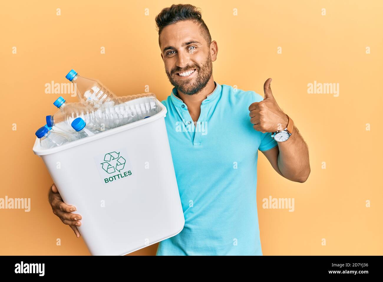 Handsome man with beard holding recycling wastebasket with plastic ...
